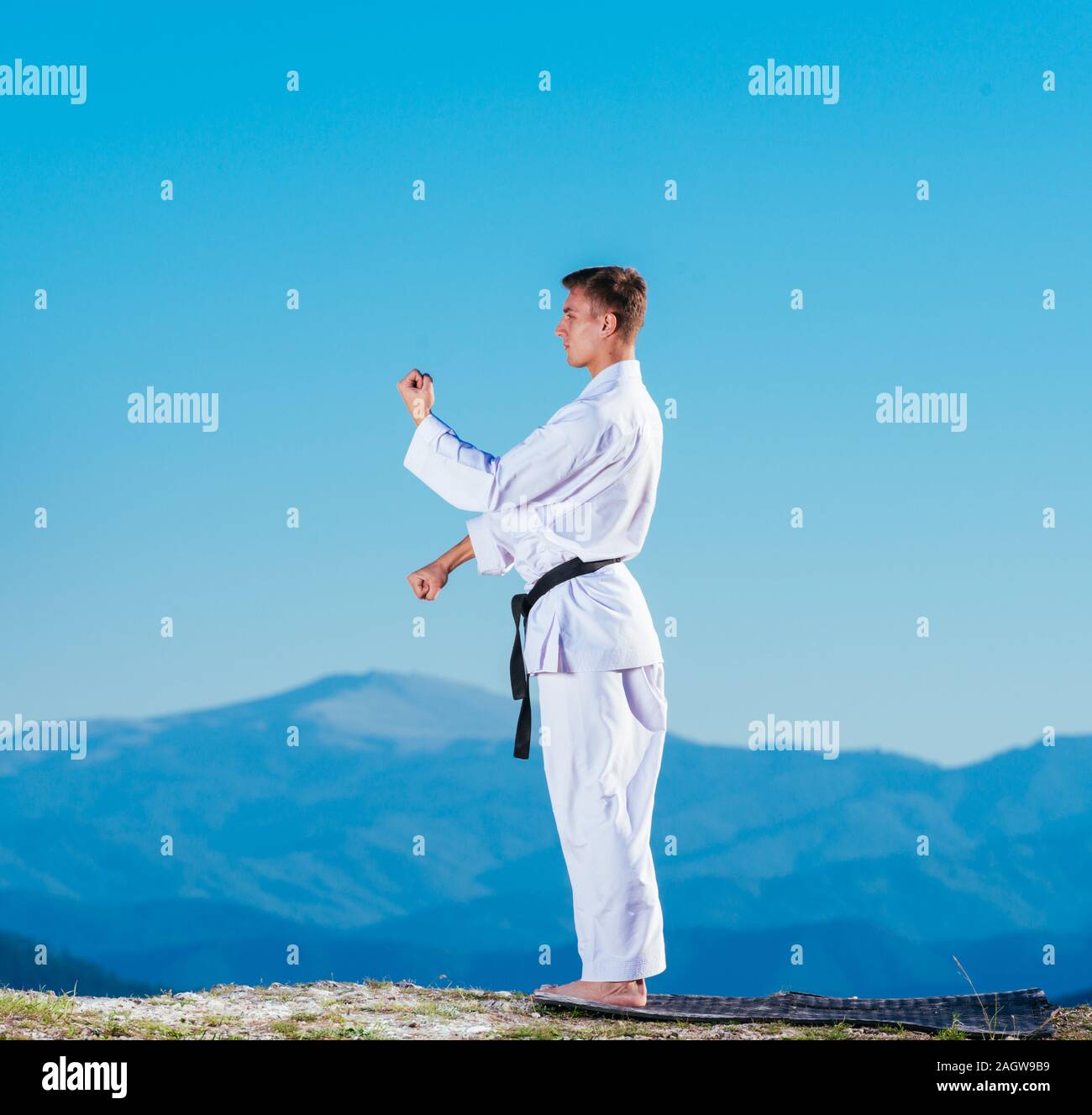 Blond karate athlete does kata on top of a mountain while performing a ...