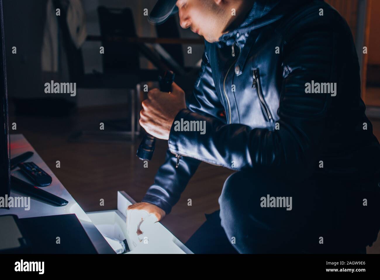 Young thief walk in the apartment and stealing from the desk Stock ...