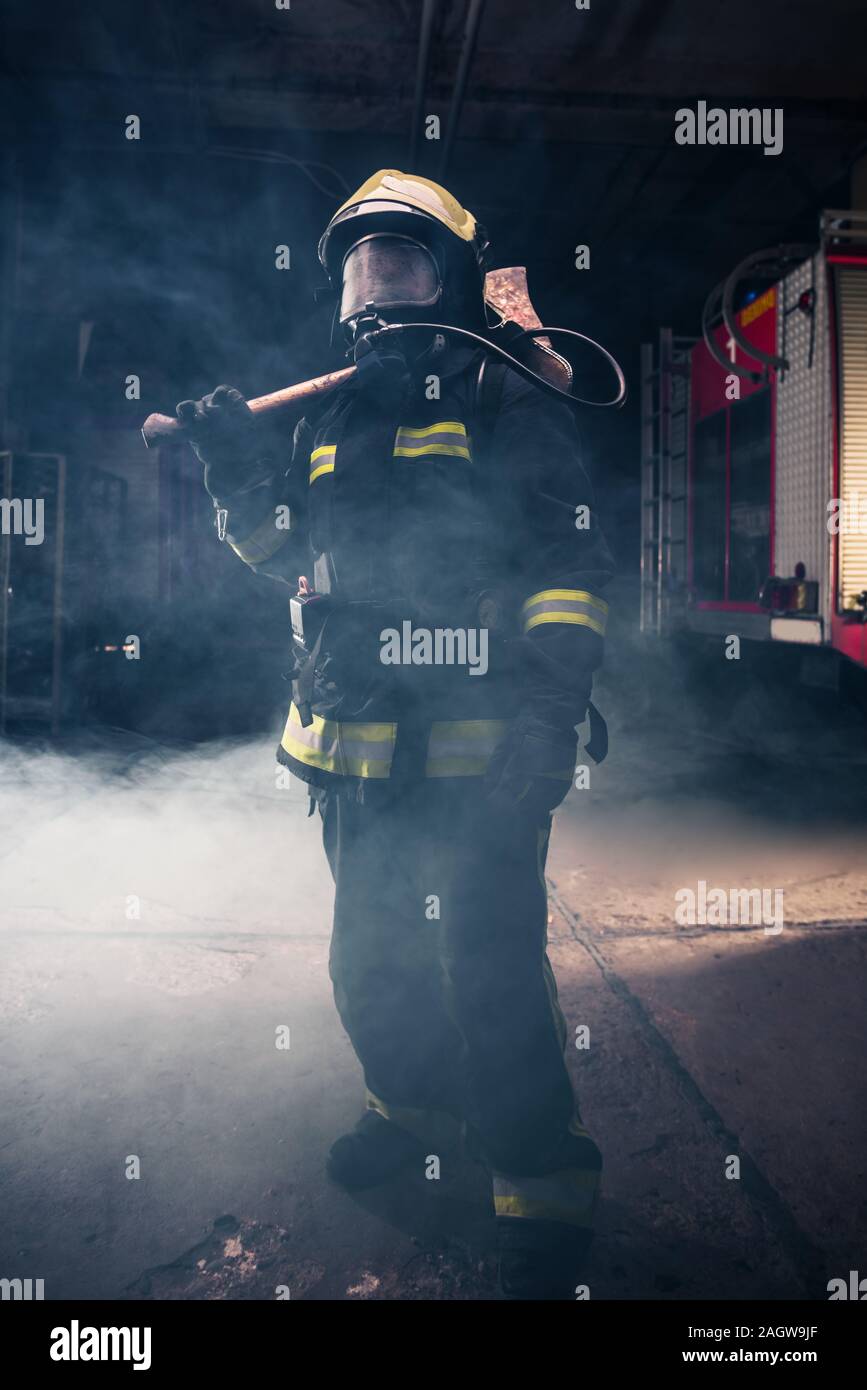 Portrait of a female firefighter while holding an axe and wearing an ...