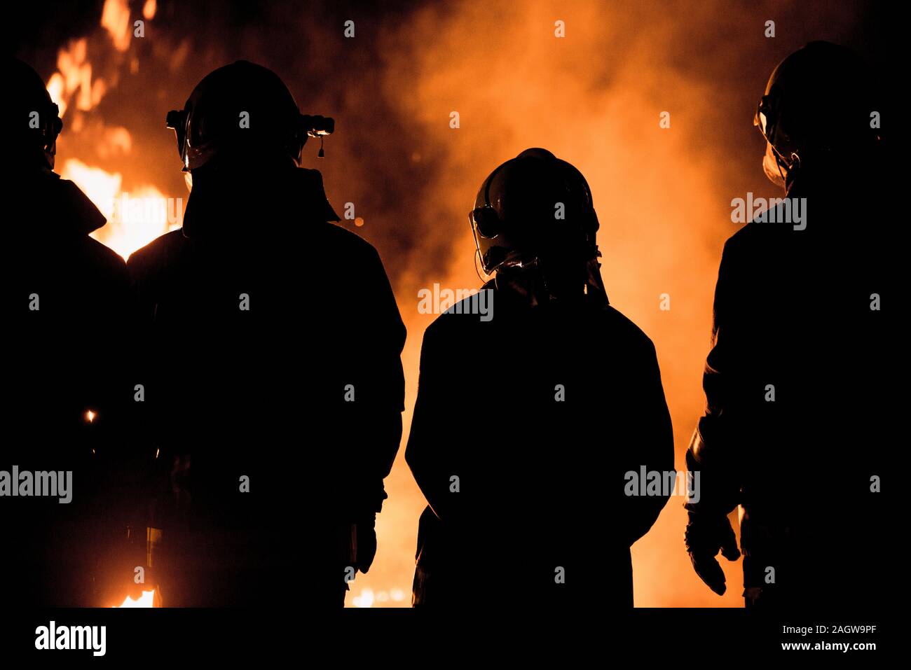 Fireman team in full equipment with helmets and gas masks fighting a ...