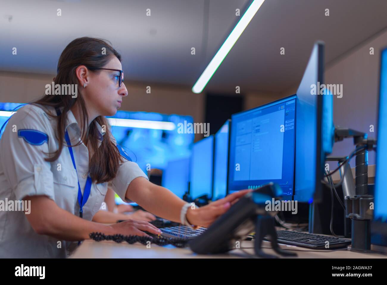 Female security guard operator talking on the phone while watching the ...