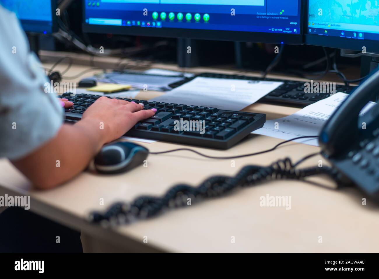 Close up photo of a security data center operator (agent )typing on her ...