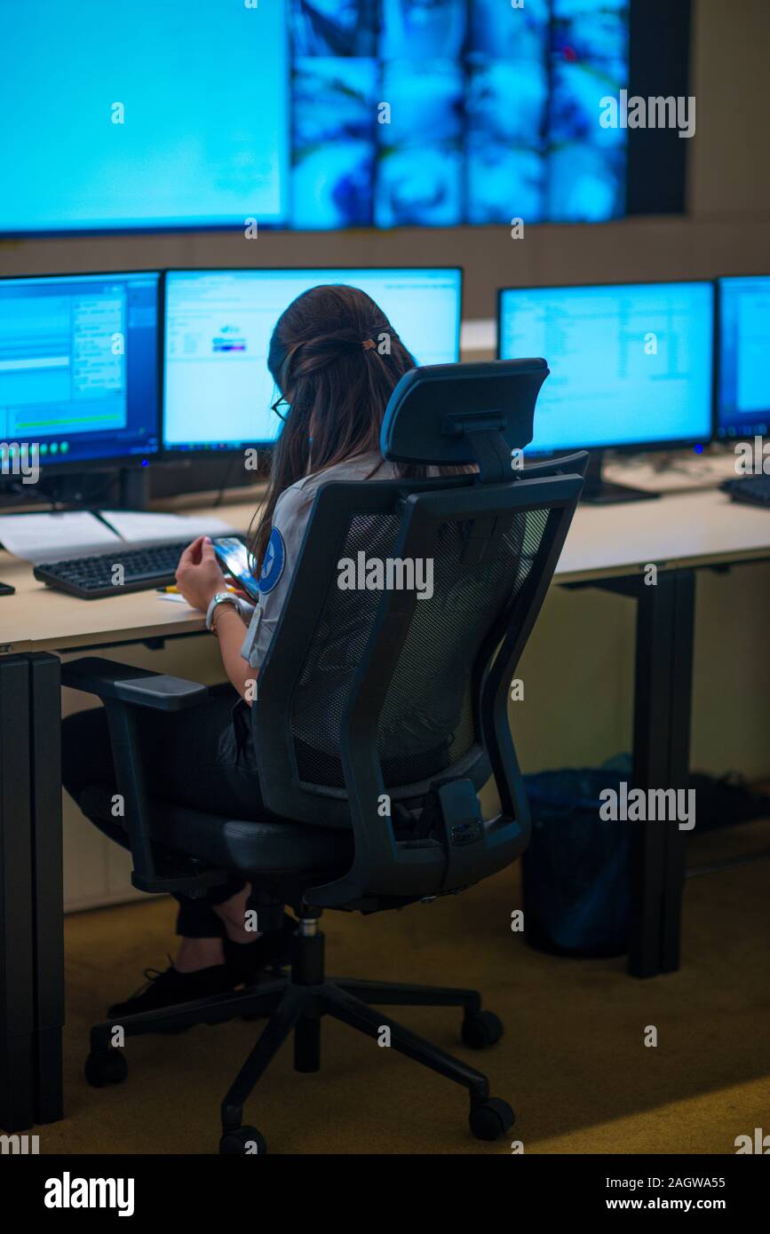 Female security guard sitting back and monitoring modern CCTV cameras ...
