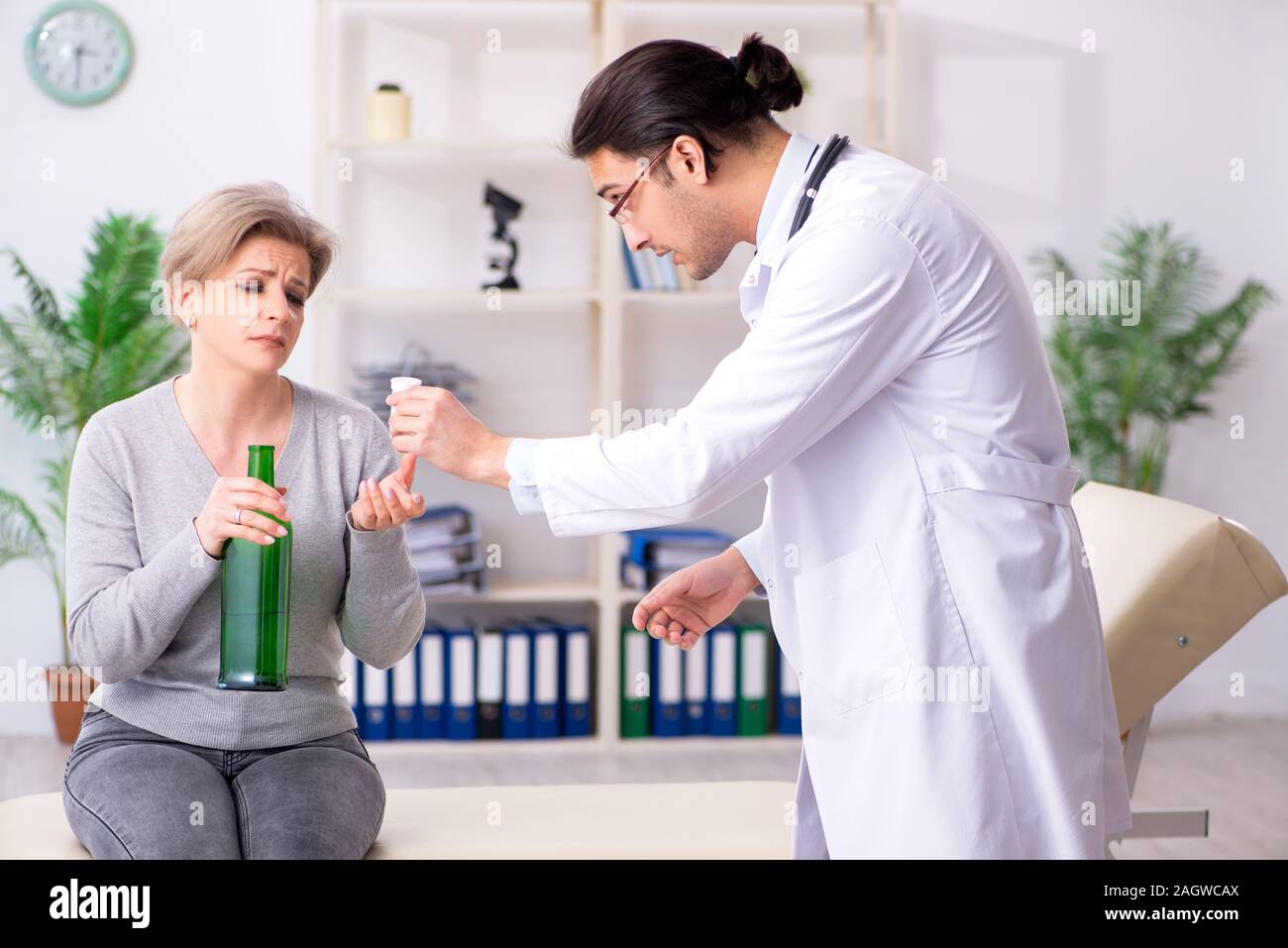 The female alcoholic visiting young male doctor Stock Photo - Alamy