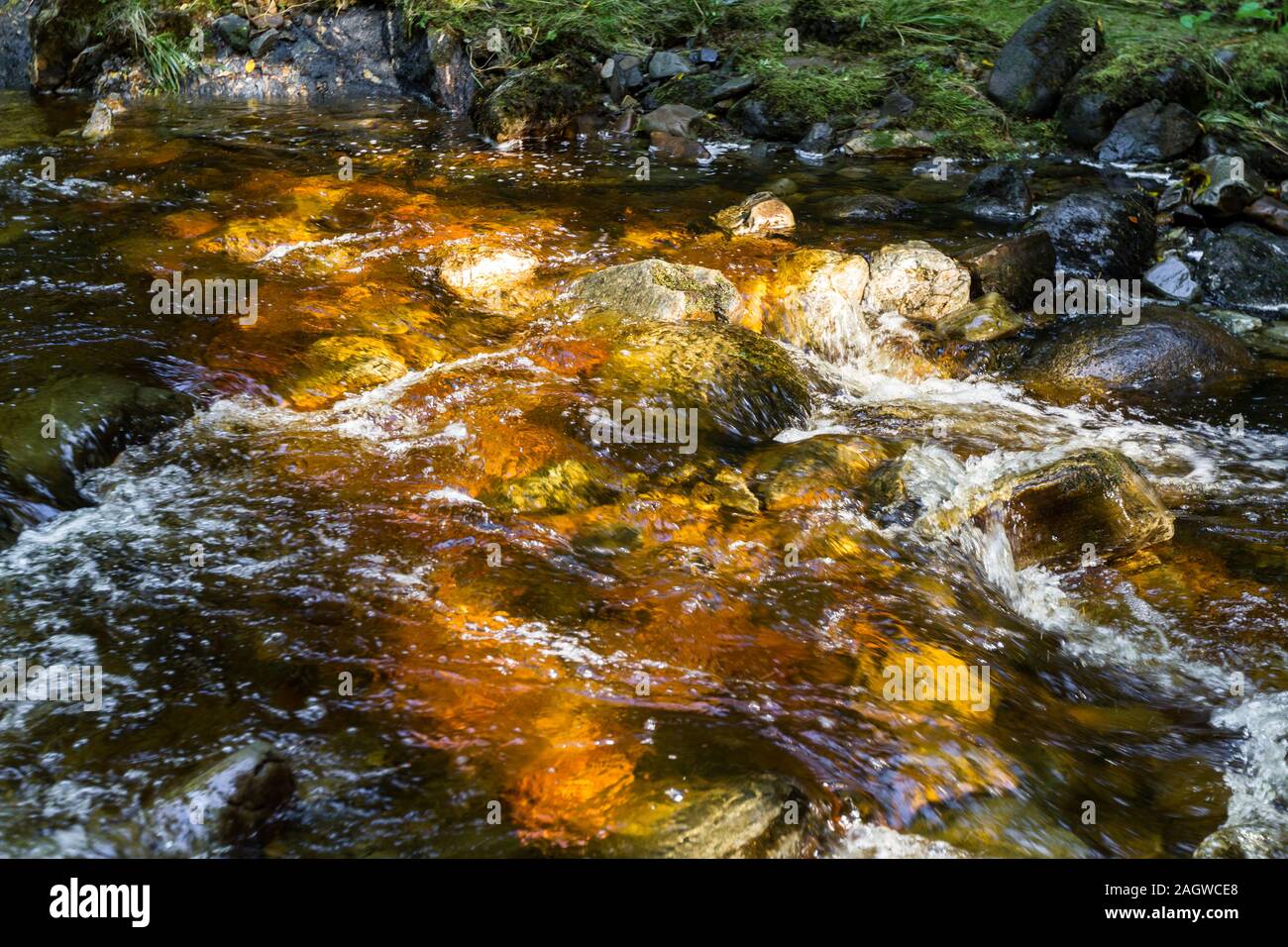 shallow burn flowing with fresh water with a reddish brown color ...