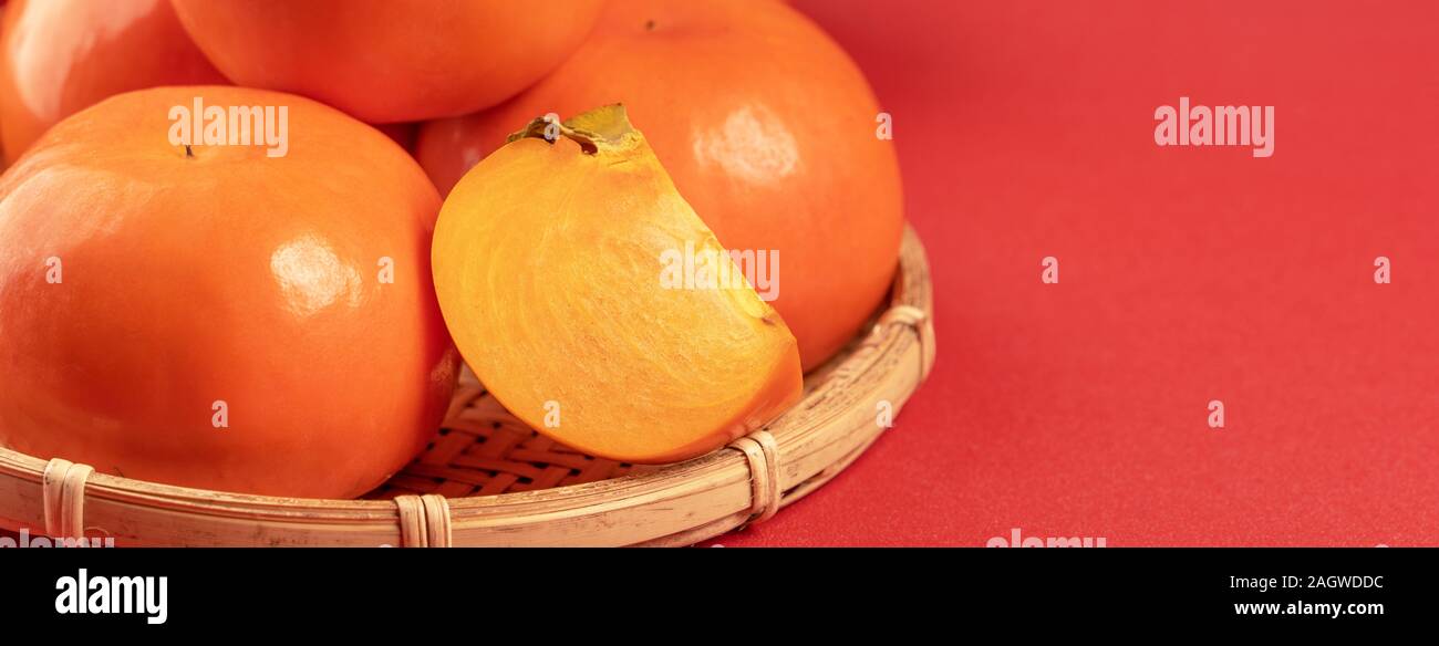 Fresh beautiful sliced sweet persimmon kaki isolated on red table ...