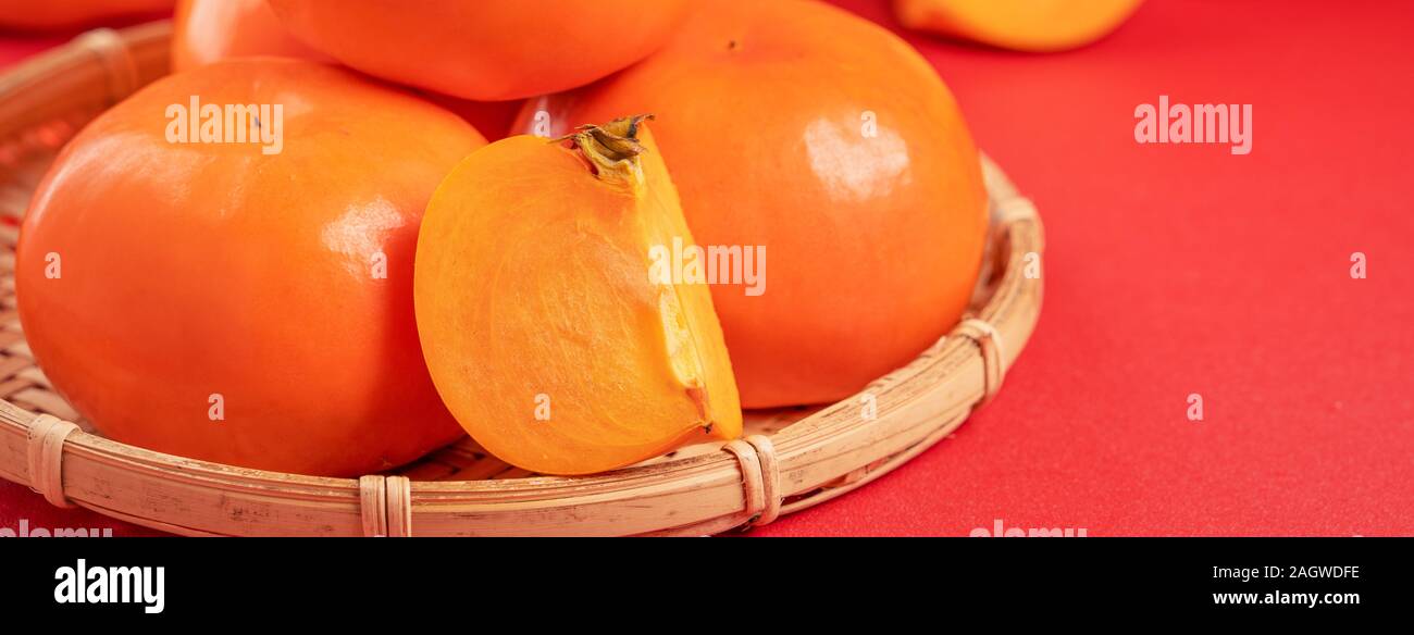 Fresh beautiful sliced sweet persimmon kaki isolated on red table ...