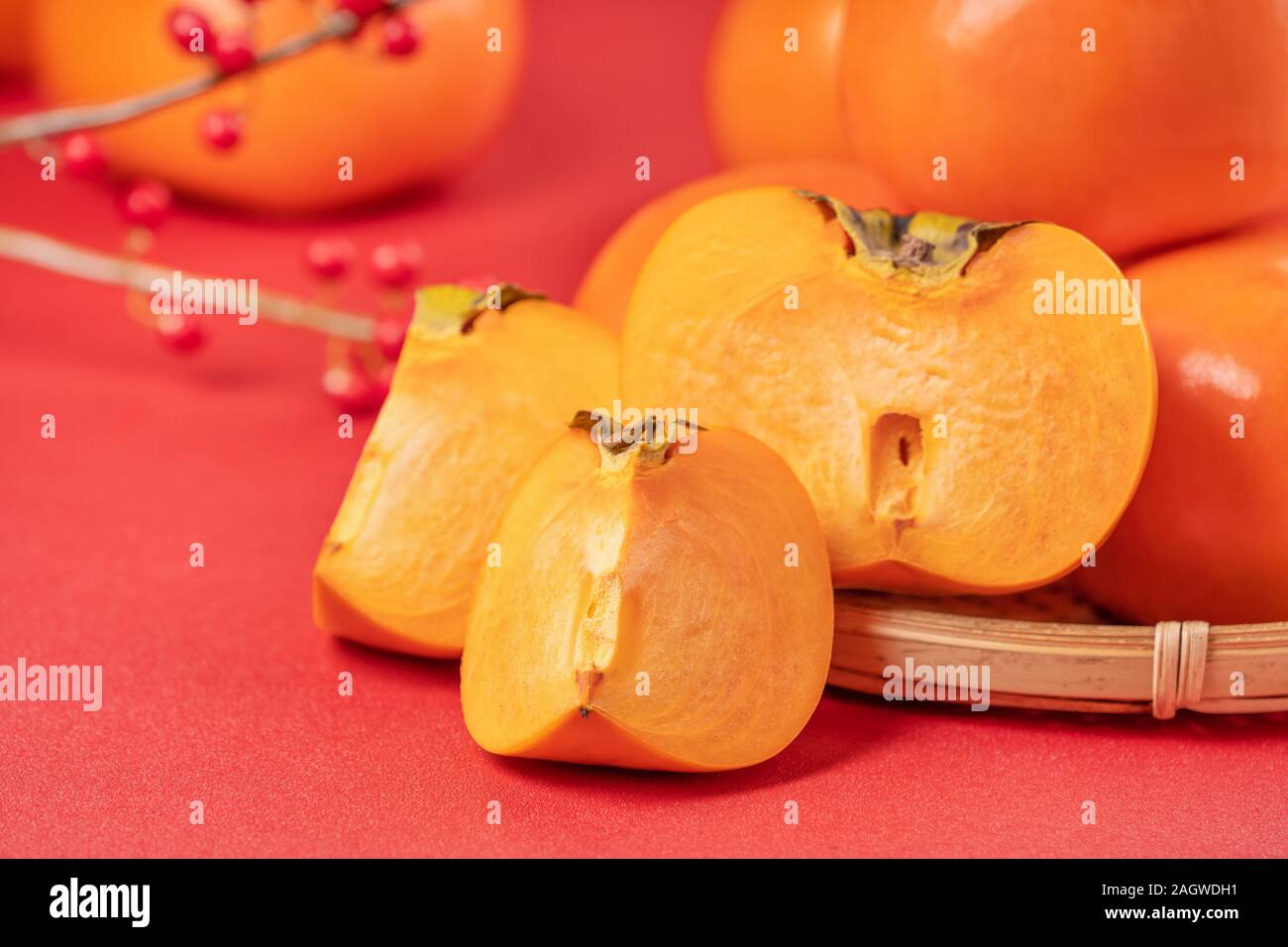 Fresh beautiful sliced sweet persimmon kaki isolated on red table ...