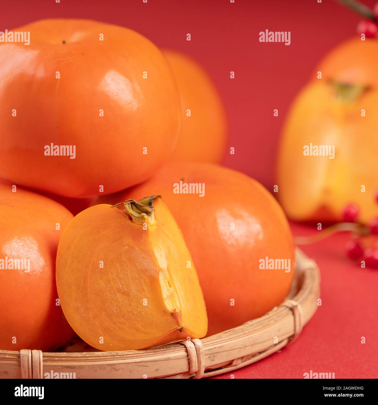 Fresh beautiful sliced sweet persimmon kaki isolated on red table ...