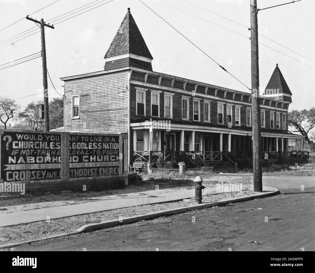 Two-story wood frame row houses with tower at either end, next to sign ...