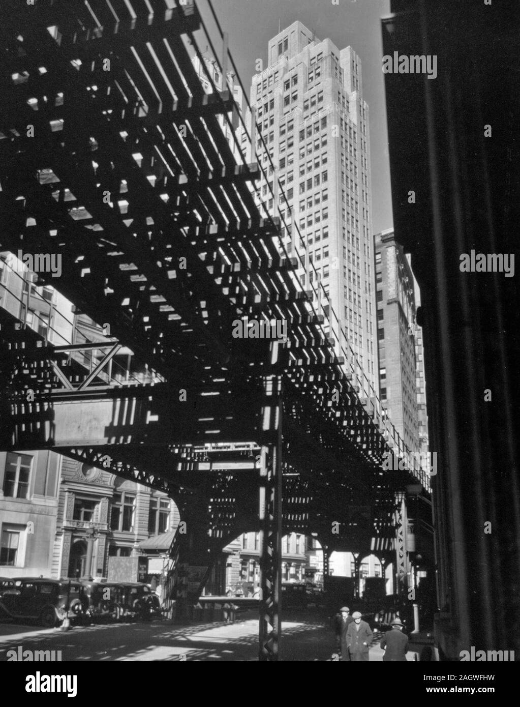Elevated railroad tracks fill street, right side a dark mass, building ...