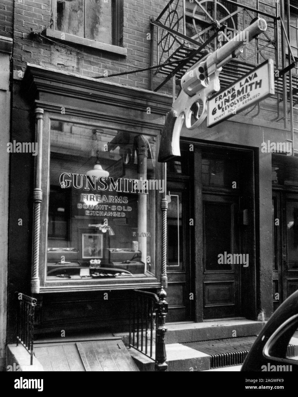 Frank Lava, gunsmith, with large wooden pistol hanging over entrance ...