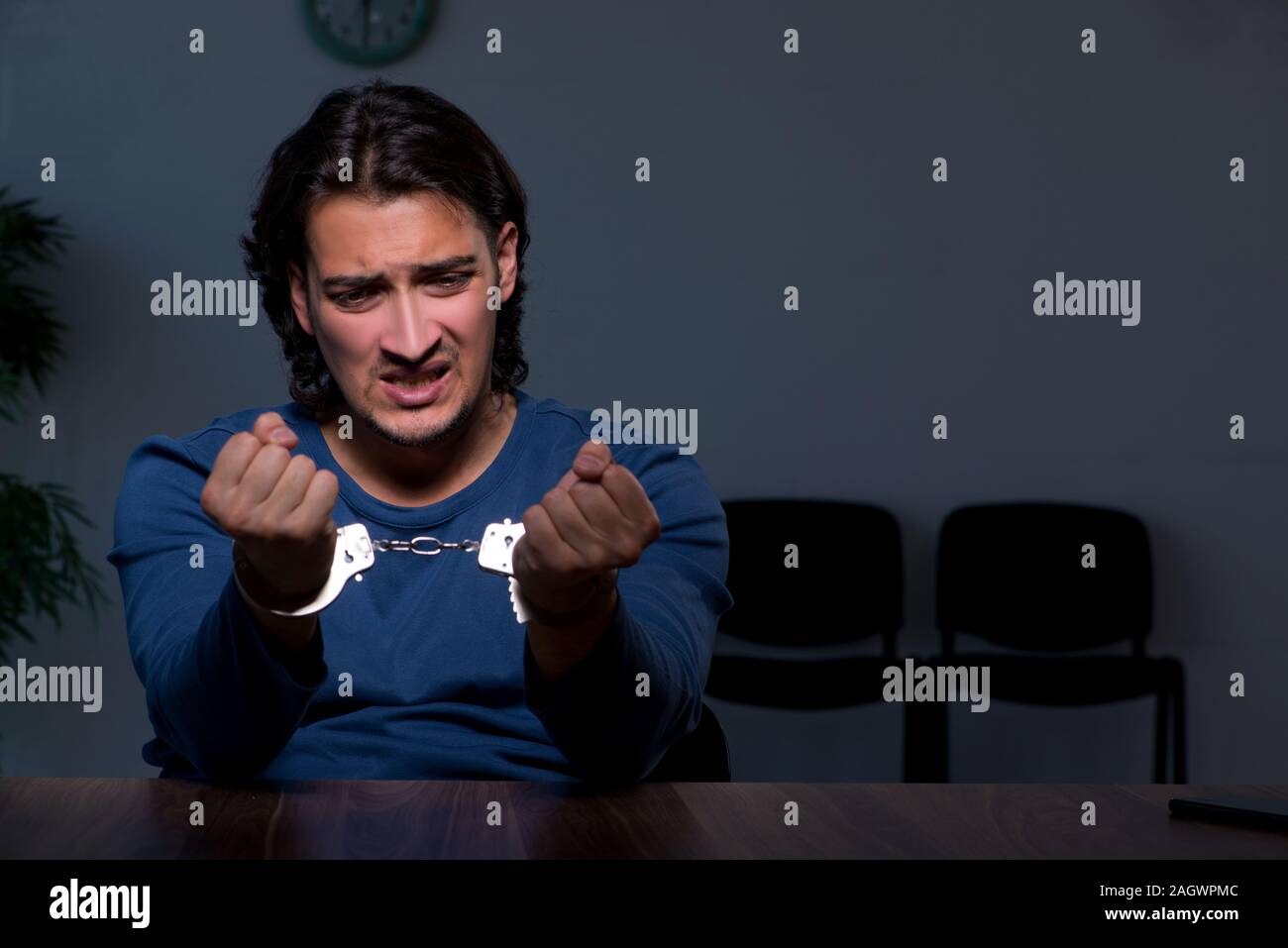 The young convict man sitting in dark room Stock Photo - Alamy