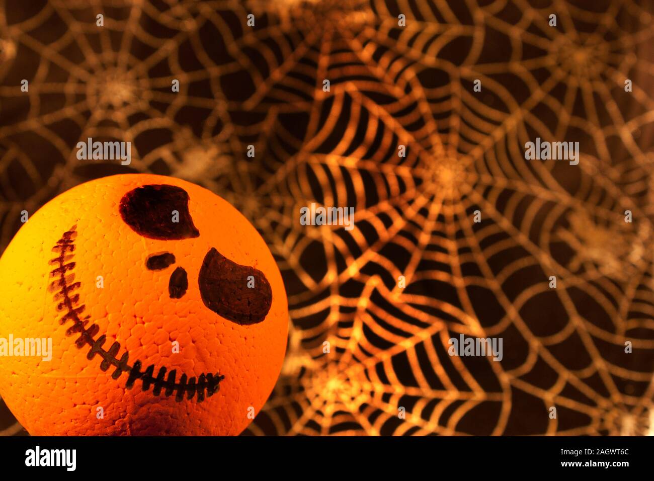 A creepy orange halloween face peers around at the camera, with a ...