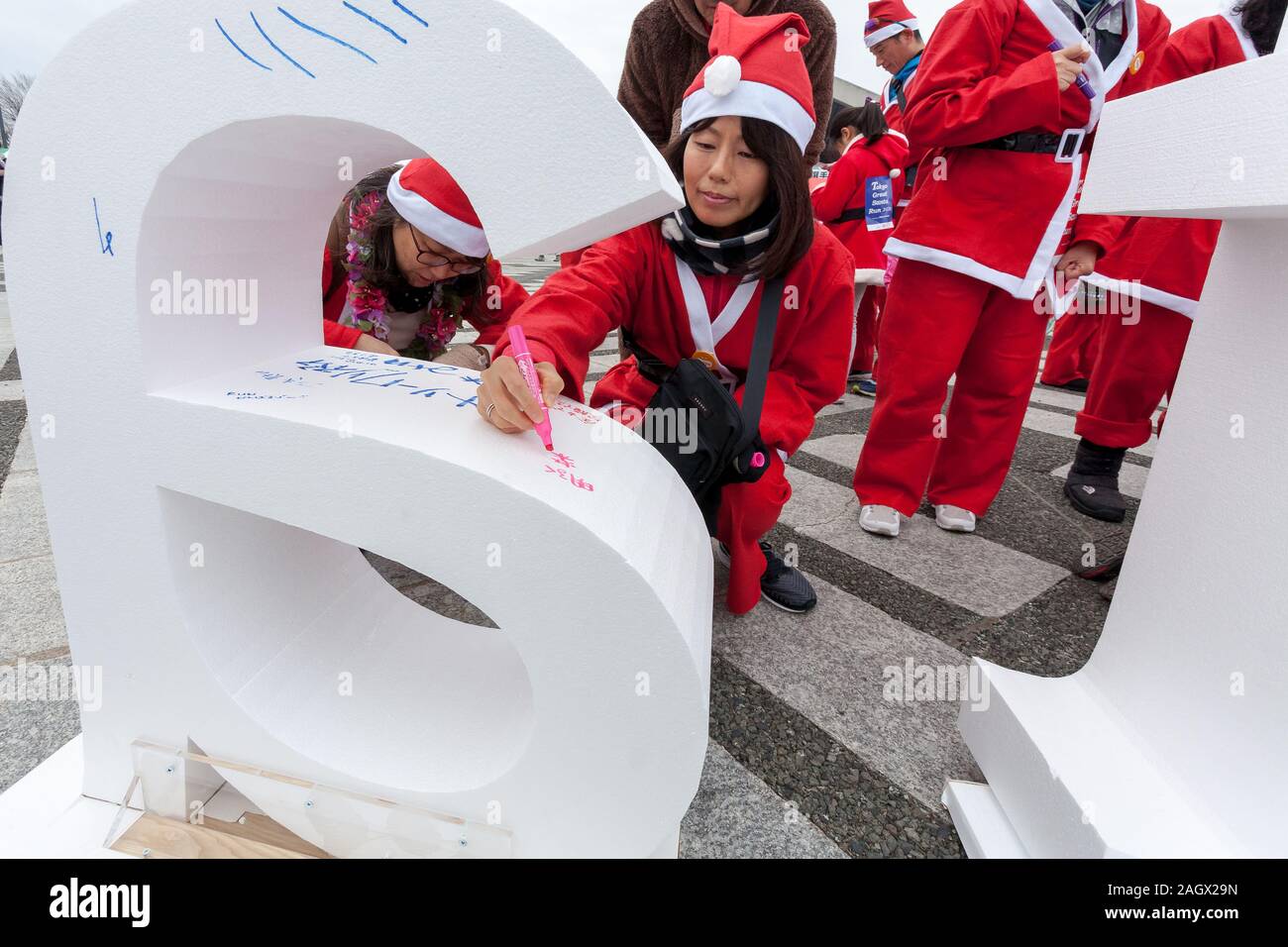 Participants write Christmas messages on large letters spelling "Santa ...