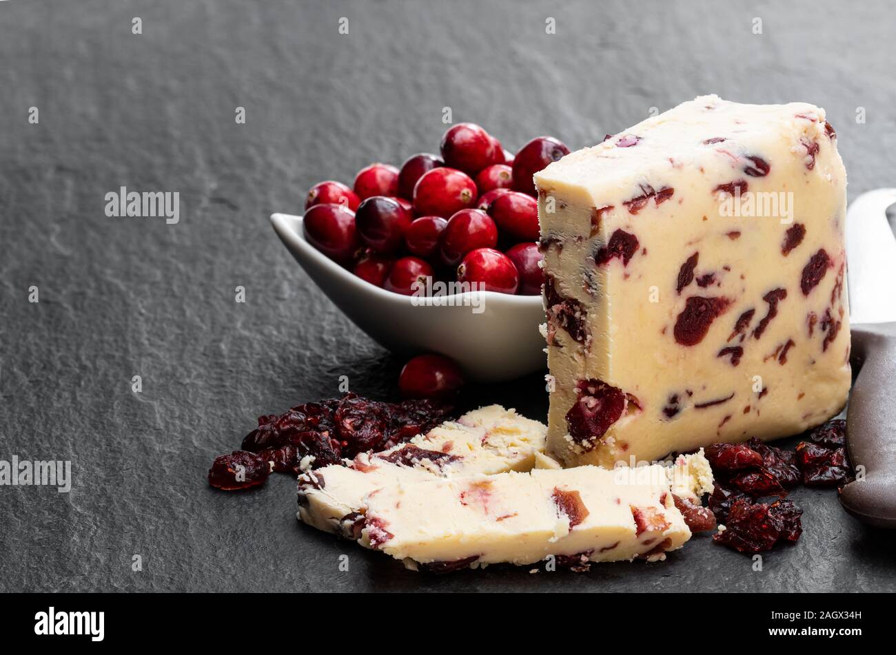 Cranberry cheddar cheese with fresh cranberry on black stone background ...