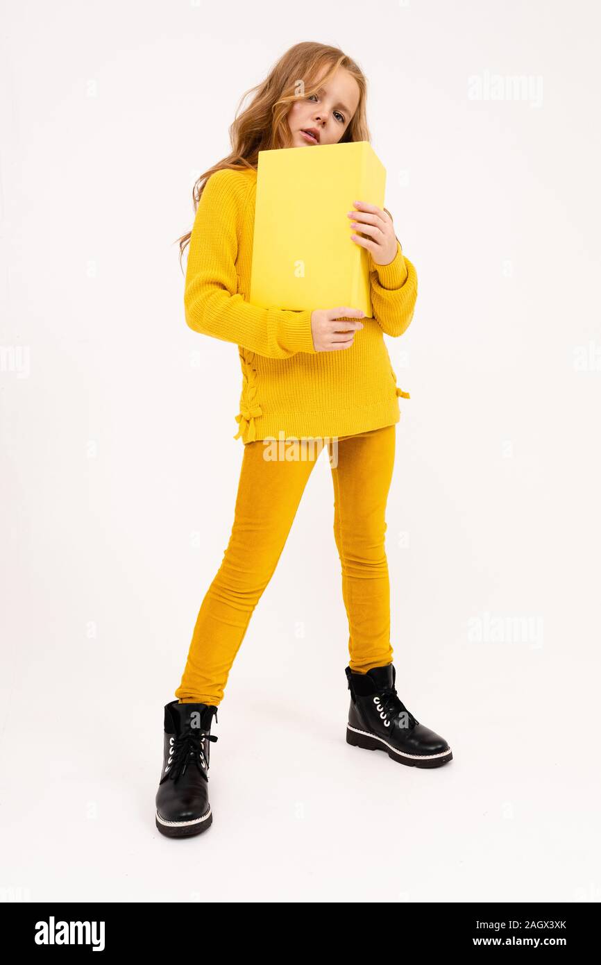 Happy teenager girl with red hair, hoody and yellow trousers read big ...