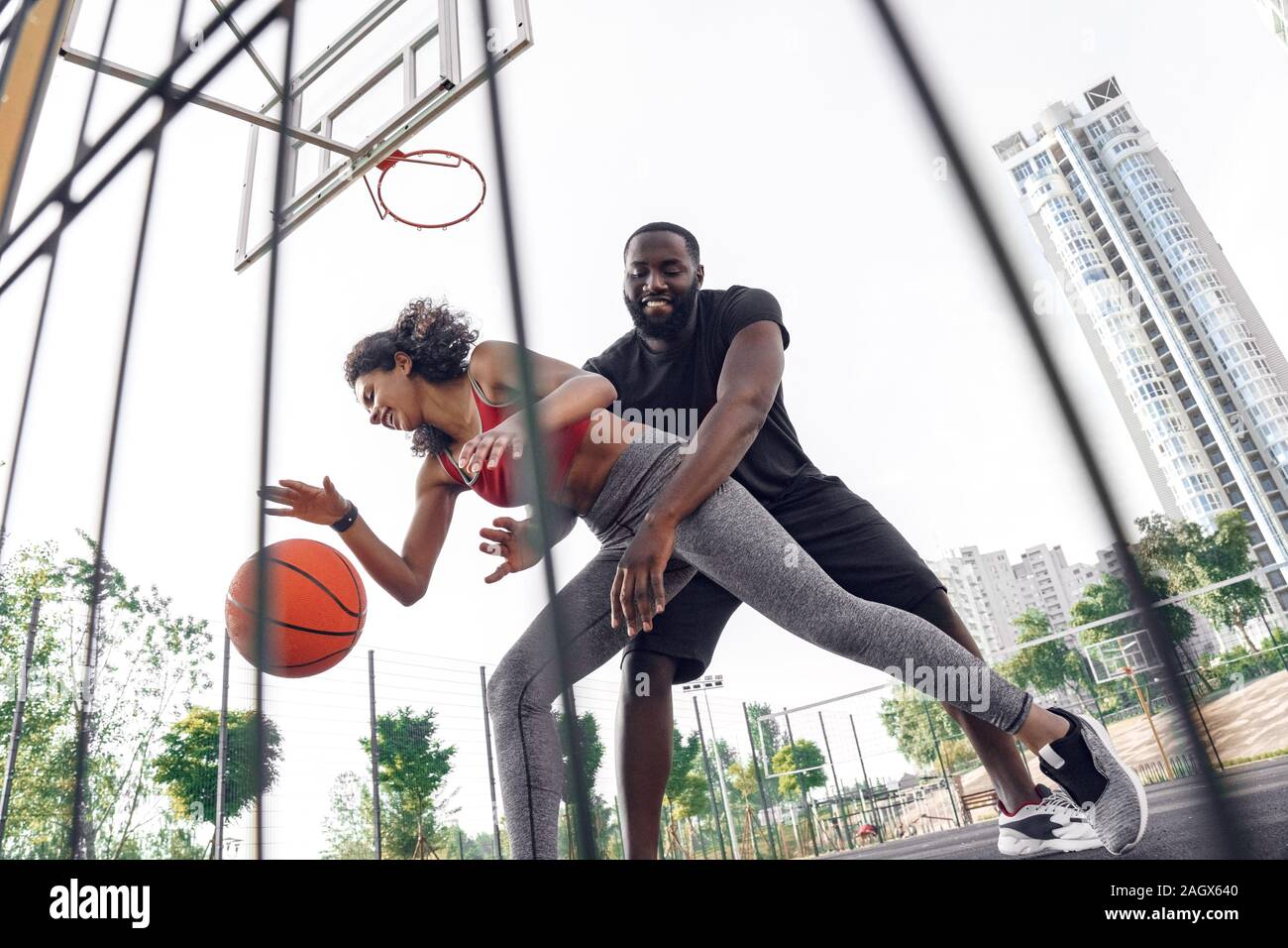 Outdoors Activity. African couple on basketball court girl dribbling ...