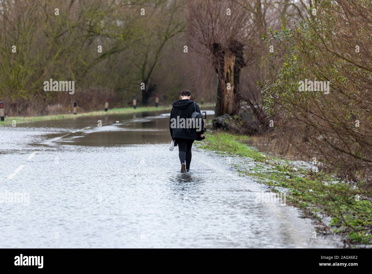 Earith, UK. 22nd Dec, 2019. A woman walks through a flooded road as the ...