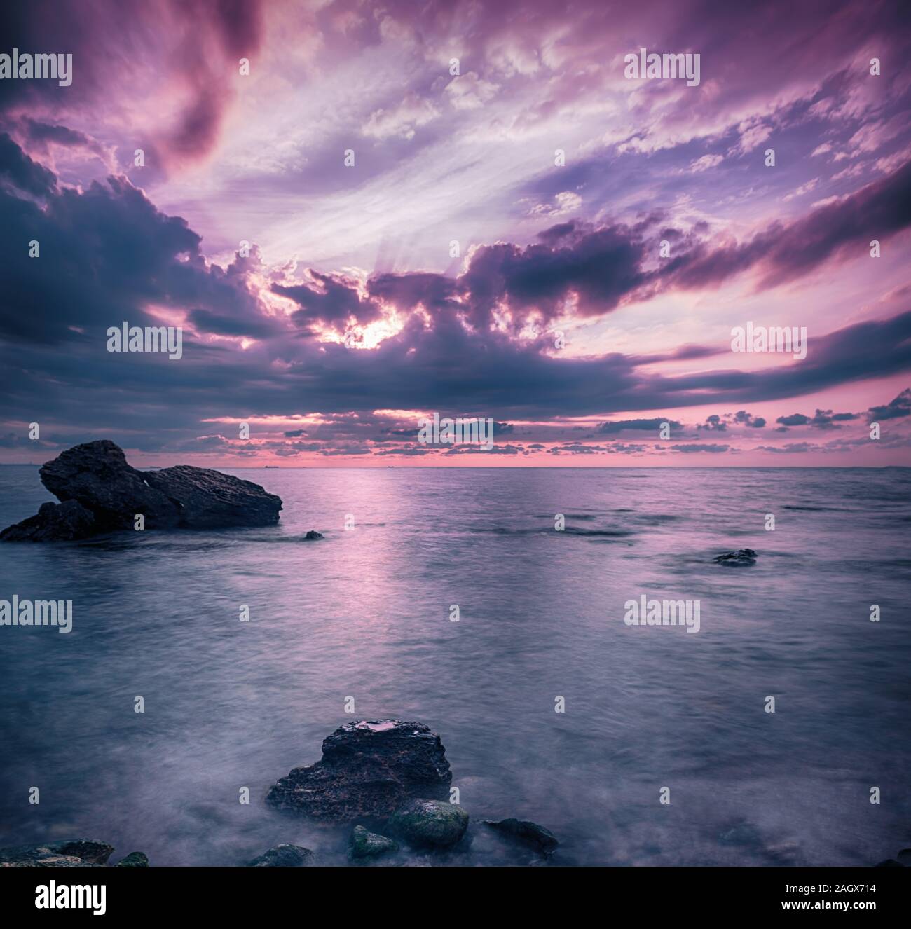 Beautiful colorful sunrise at the sea with dramatic clouds and boulders ...