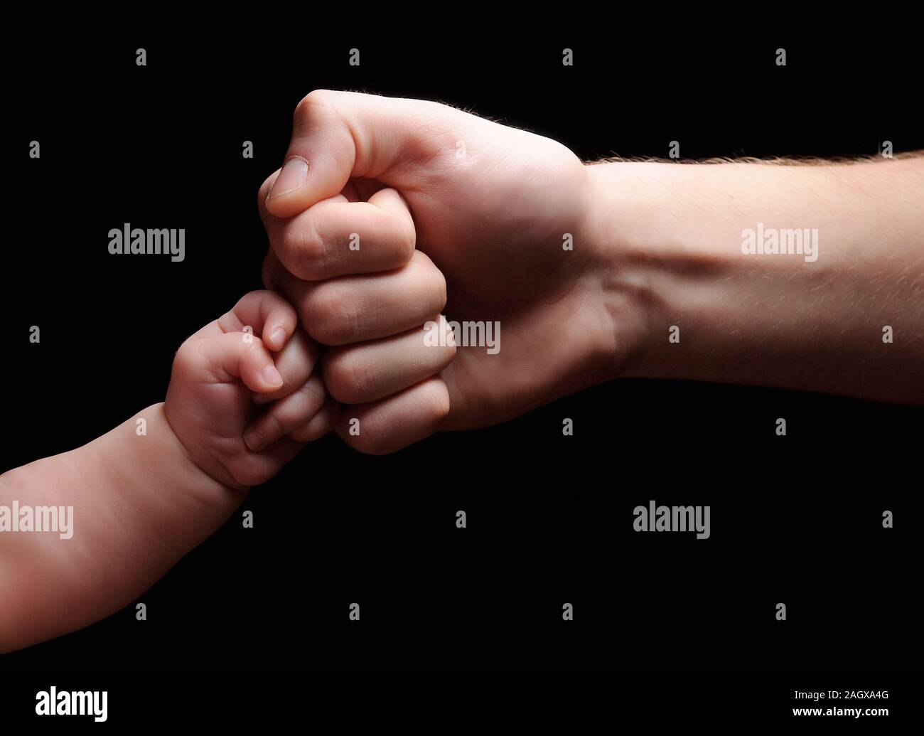 The hands of the child and the father. The fists are together. Black ...