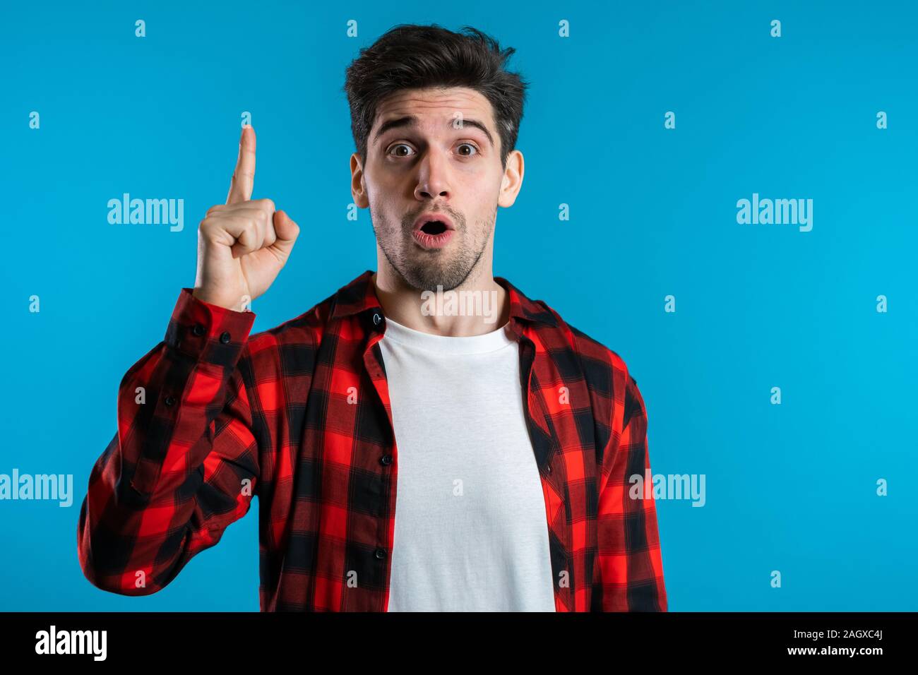 Portrait of young thinking man in red having idea moment pointing ...