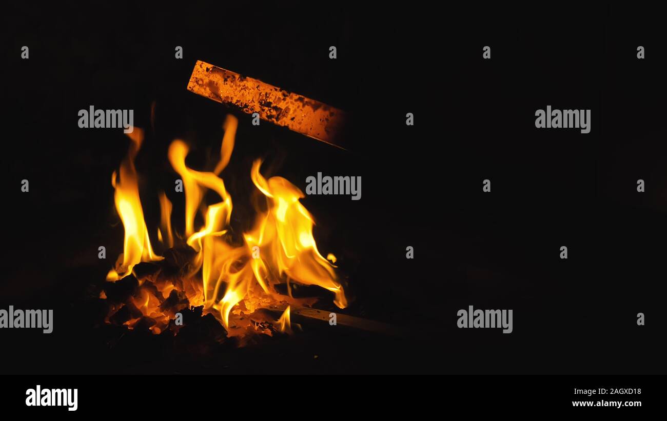 Forge fire in furnace. Blacksmith tempers a steel product in a stove ...