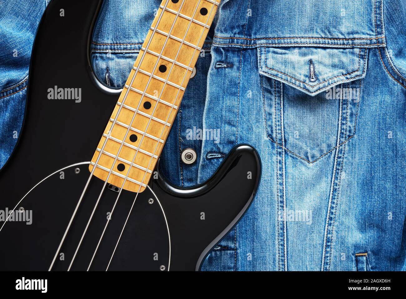 Black bass guitar on vintage denim jeans jacket for music background ...