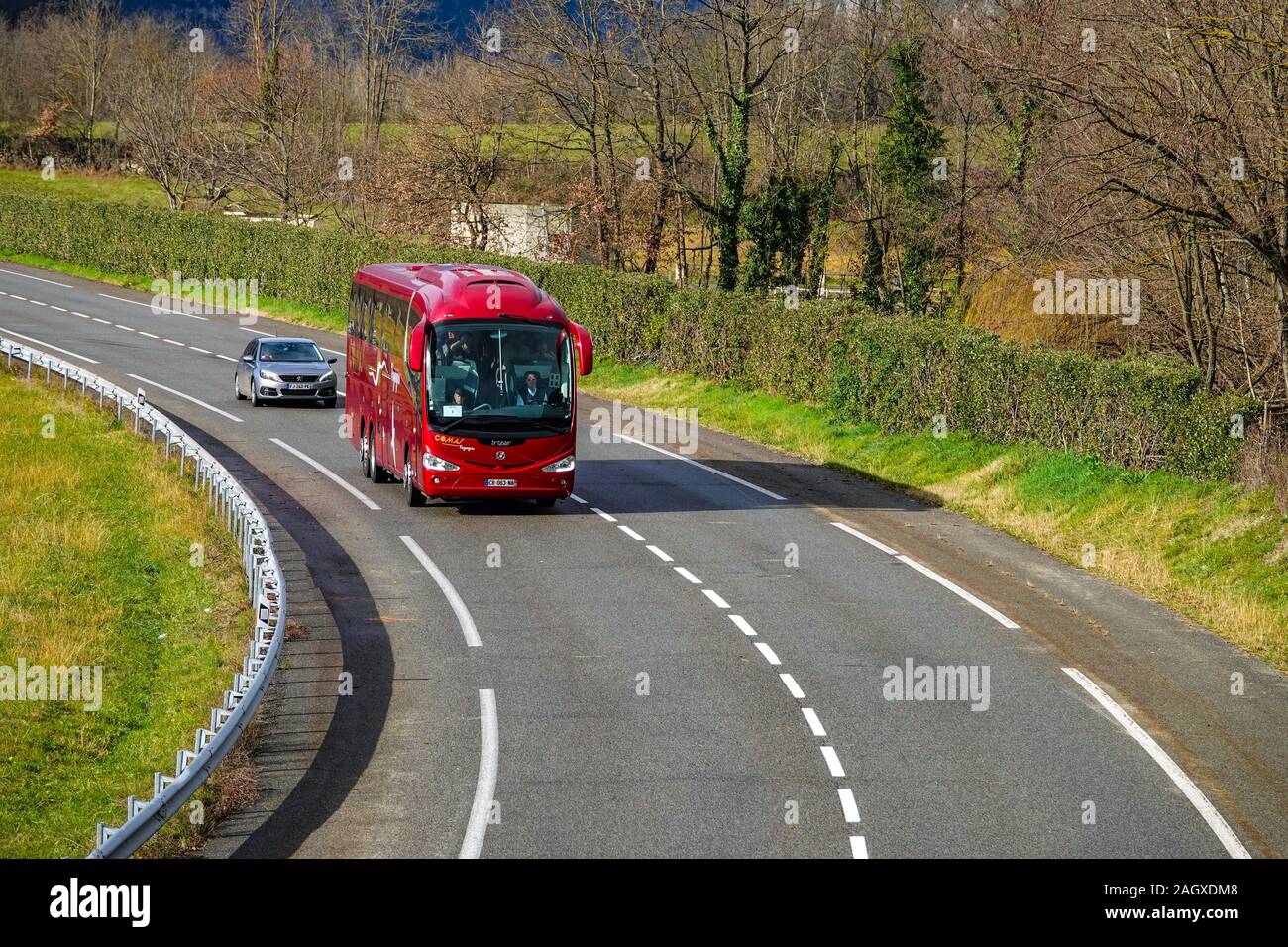 Big red bus driving on the right on dry road with bend, France Stock ...