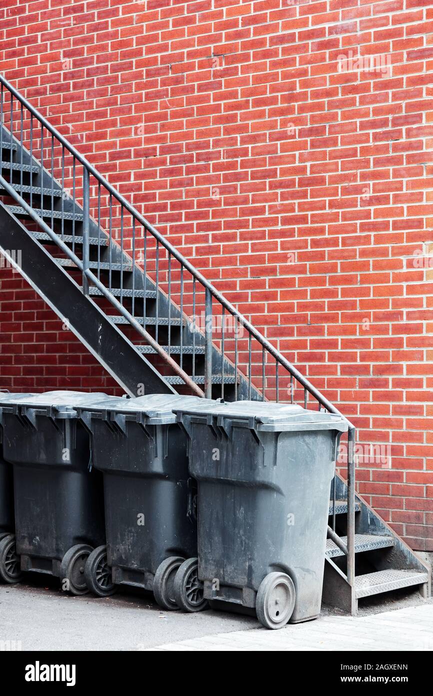 Black trash garbage bins near the outdoor stairs of a restaurant with ...