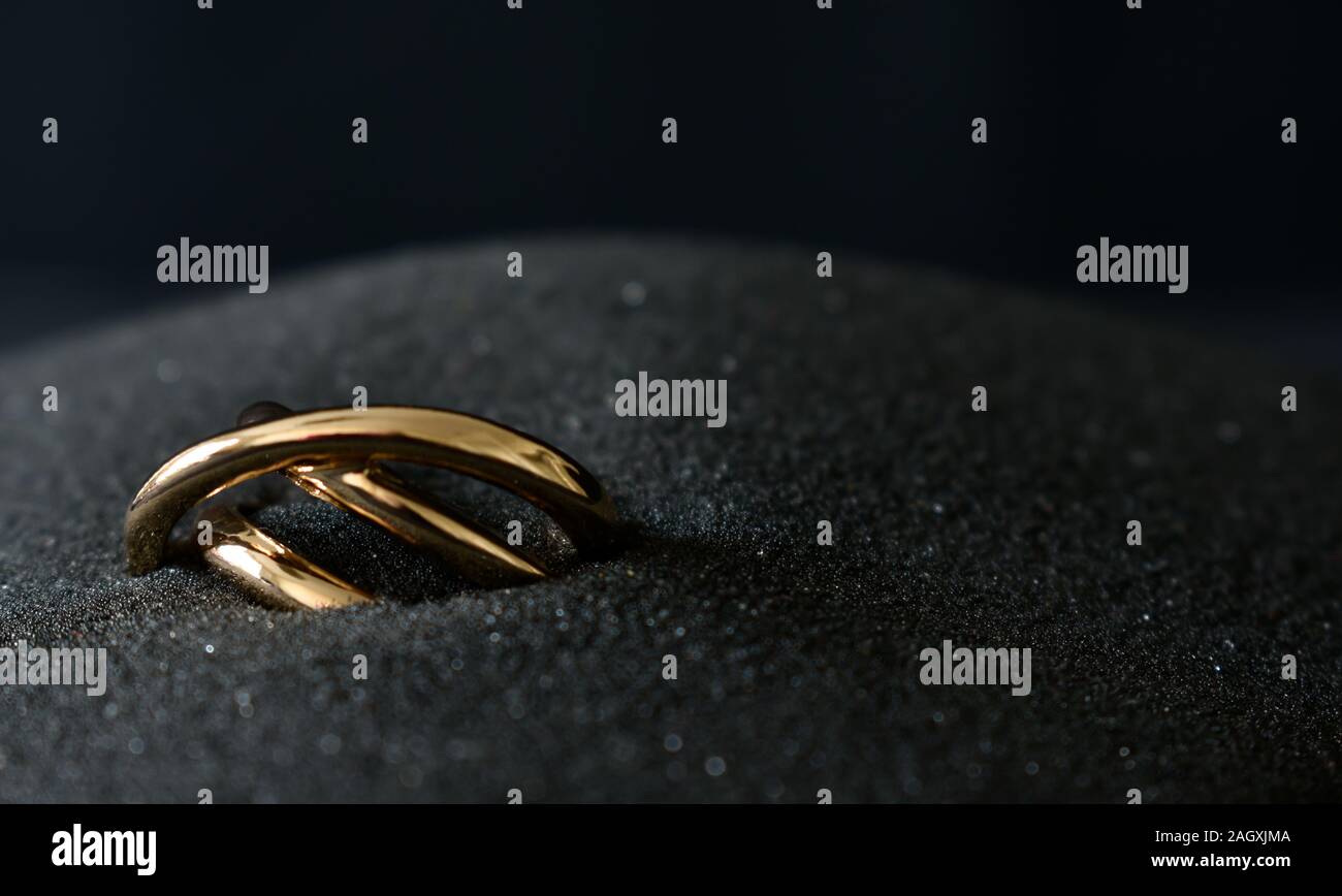 Gold ring cover by black sand Stock Photo - Alamy