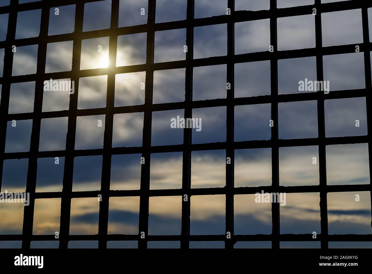 Look through the bars at the sky. Pale sunlight breaking through the ...