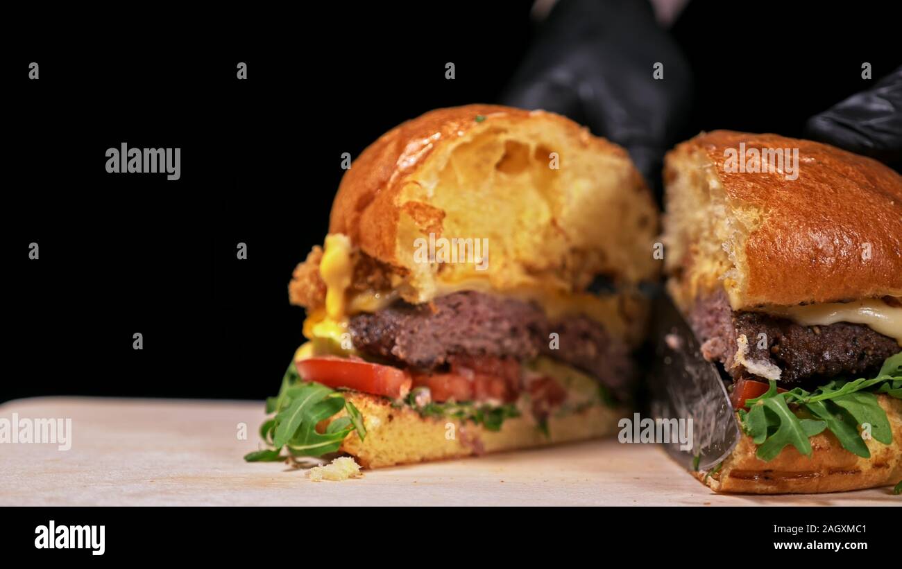 Cut craft burger is cooking on black background. Consist: sauce ...