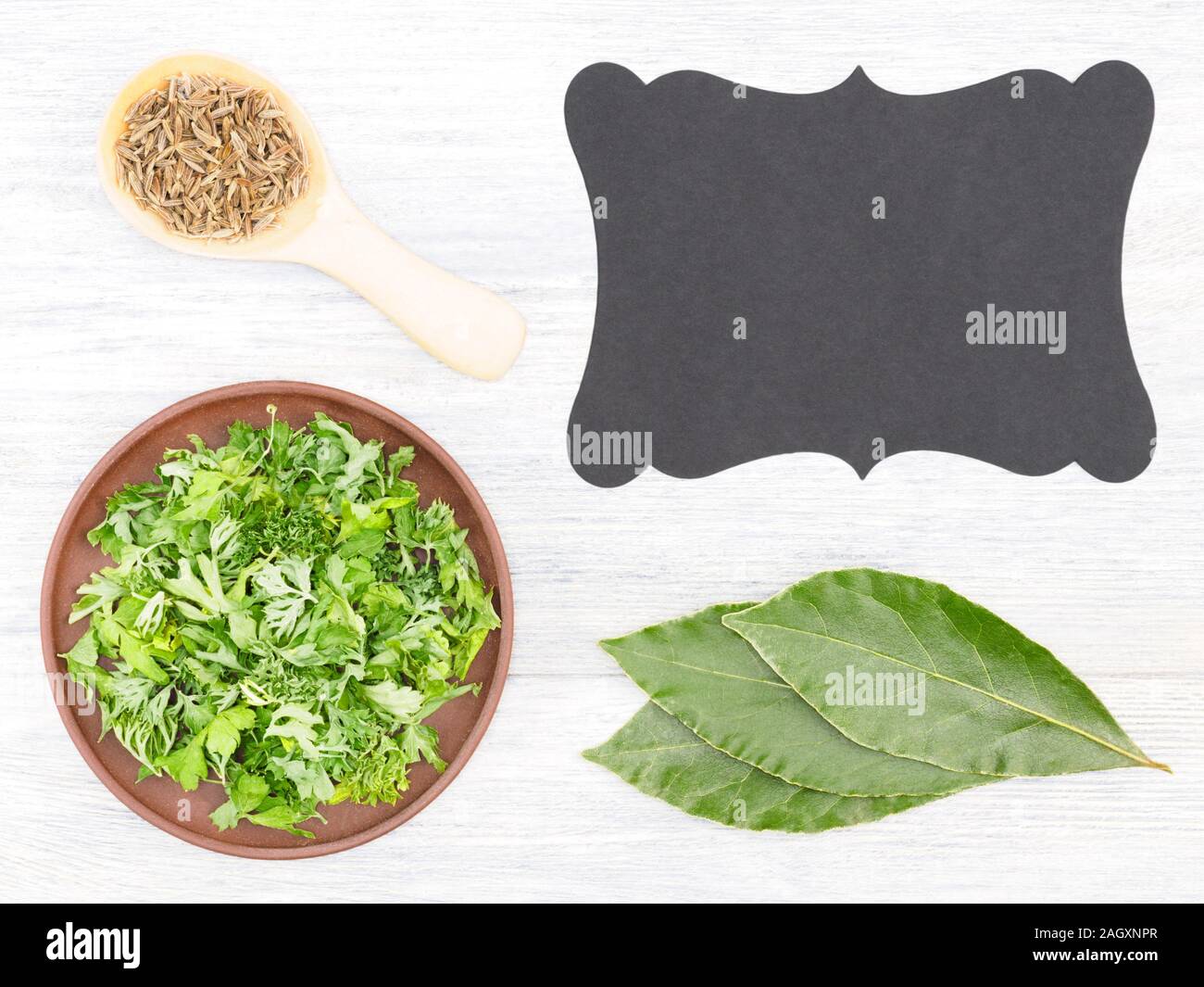 Green herb, cumin (jeera), bay leaf, nameplate on a white wooden ...