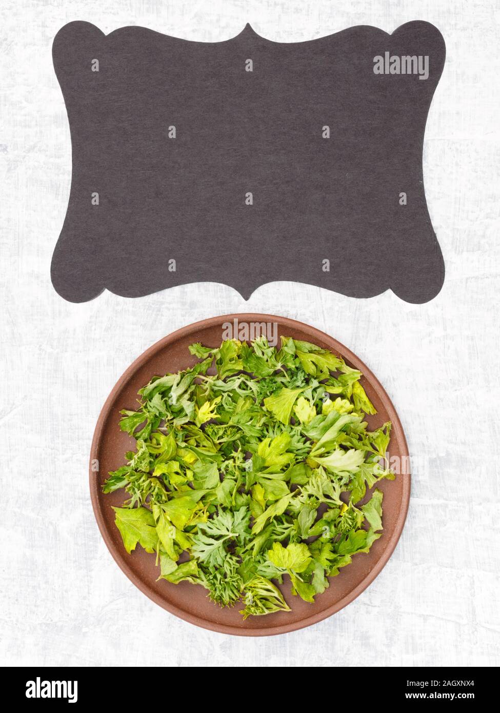 Green herb in clay plate, nameplate on a white concrete background with ...
