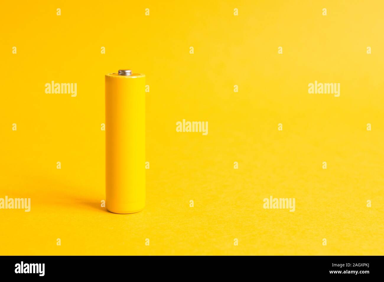 Single yellow battery on a yellow pastel background with space for text ...