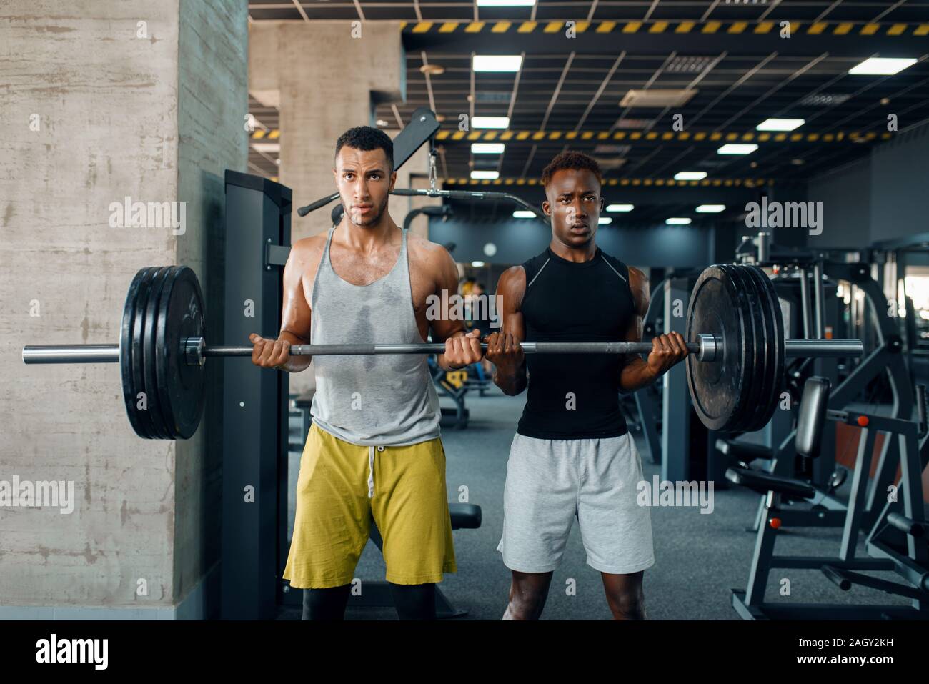 Two muscular men poses with heavy barbell in gym Stock Photo - Alamy