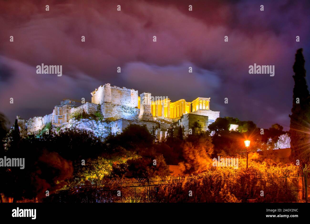 Illuminated Acropolis with Parthenon at night with the hill of Lycabetus and nice clouds, Athens ...