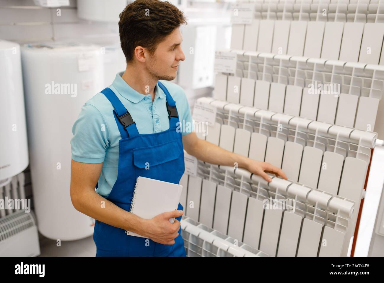 Plumber in uniform choosing water heating radiator Stock Photo - Alamy