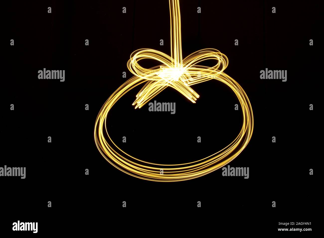 Light painting photograph of a bauble shape outline, vibrant neon gold ...