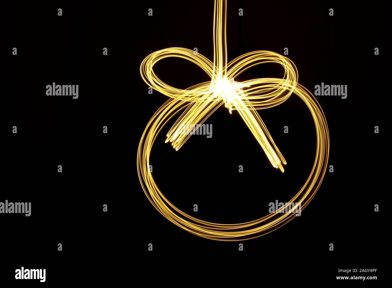 Light painting photograph of a bauble shape outline, vibrant neon gold ...