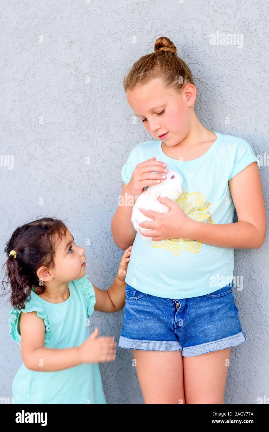 Teenager child holding a cute little white rabbit. Two happy young ...