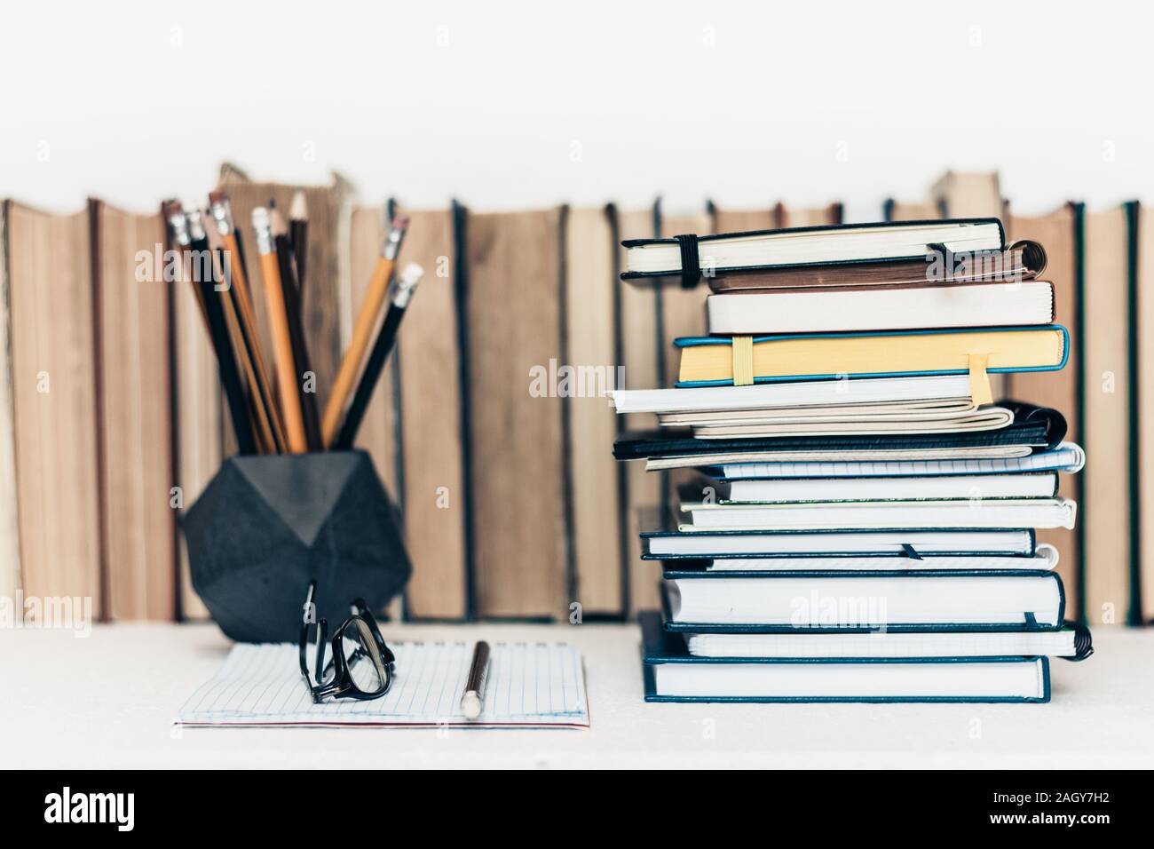 Pile of notebooks, many books and textbooks, glasses and pencils in ...
