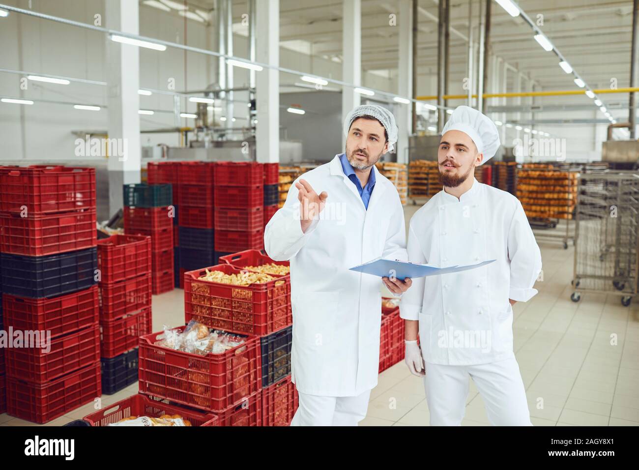 The technologist and baker speak in a bread factory. Factory workers in ...