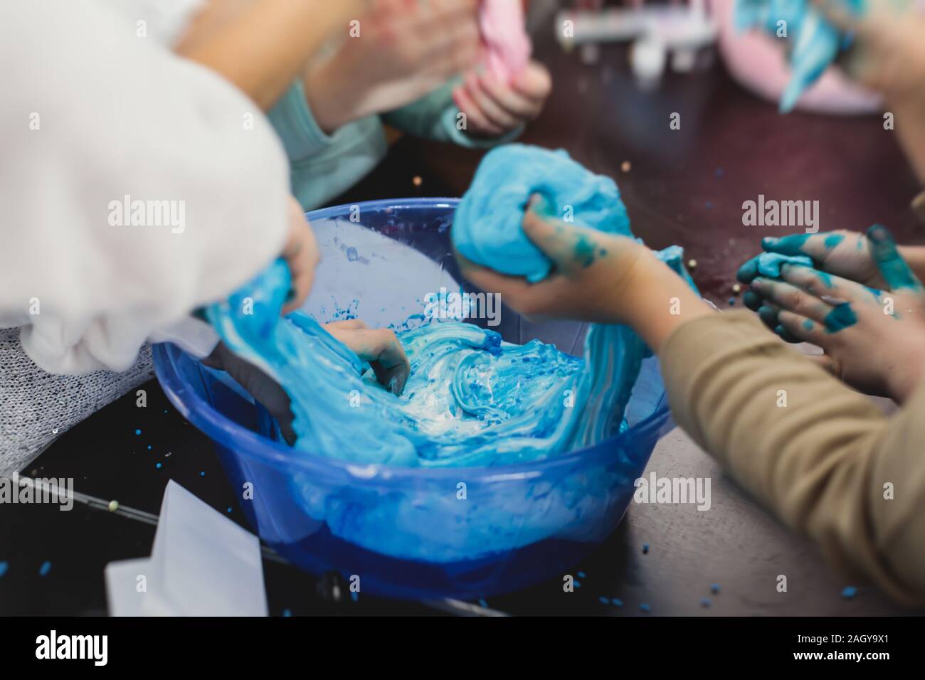 Group of kids making a multicoloured slime, pink, blue and white slime ...
