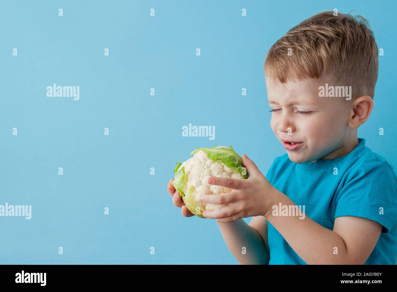 Little Boy Holding Broccoli in his hands on blue background, diet and ...