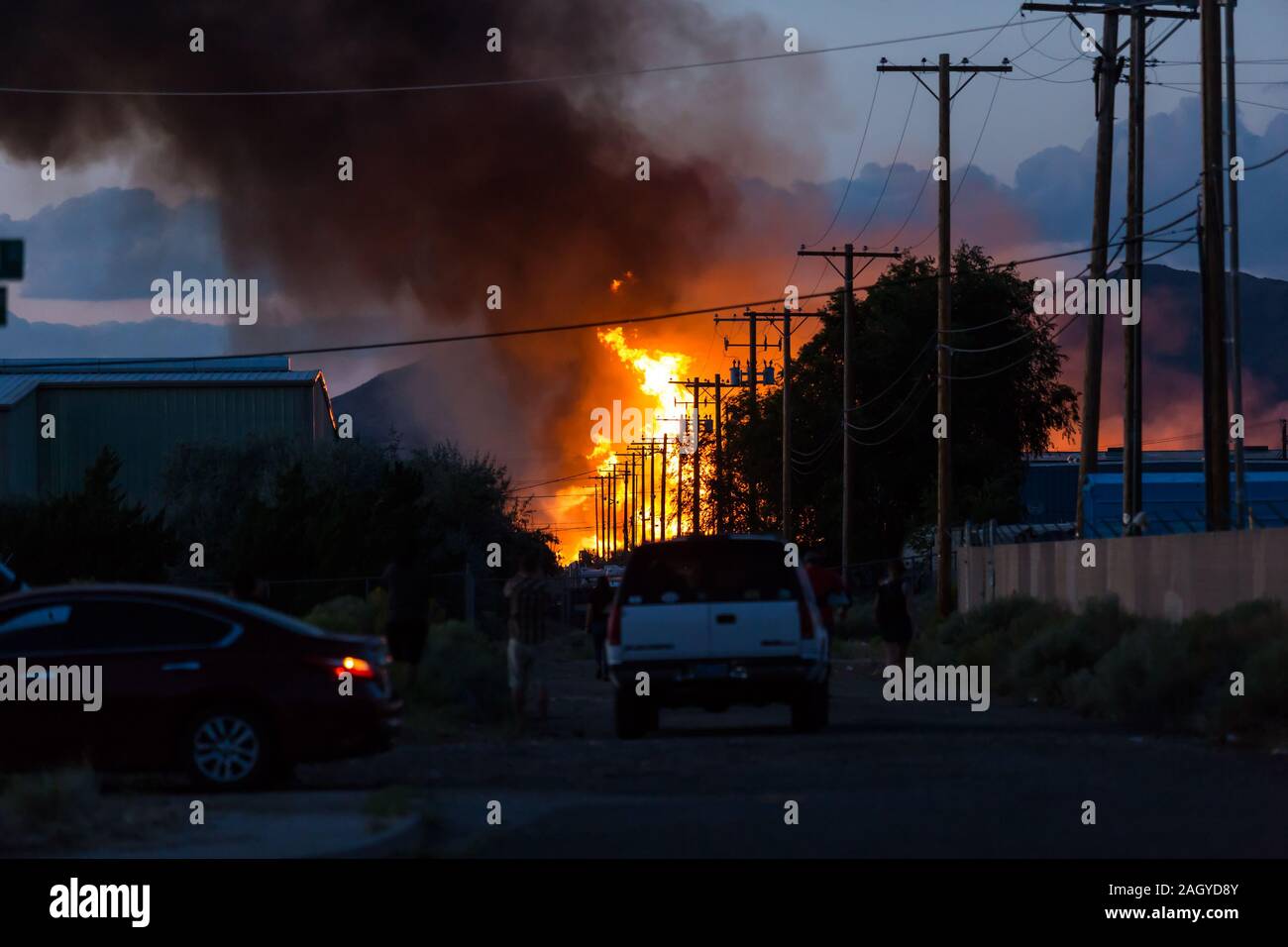 Large warehouse fire in the distance beyond spectators sitting in their ...