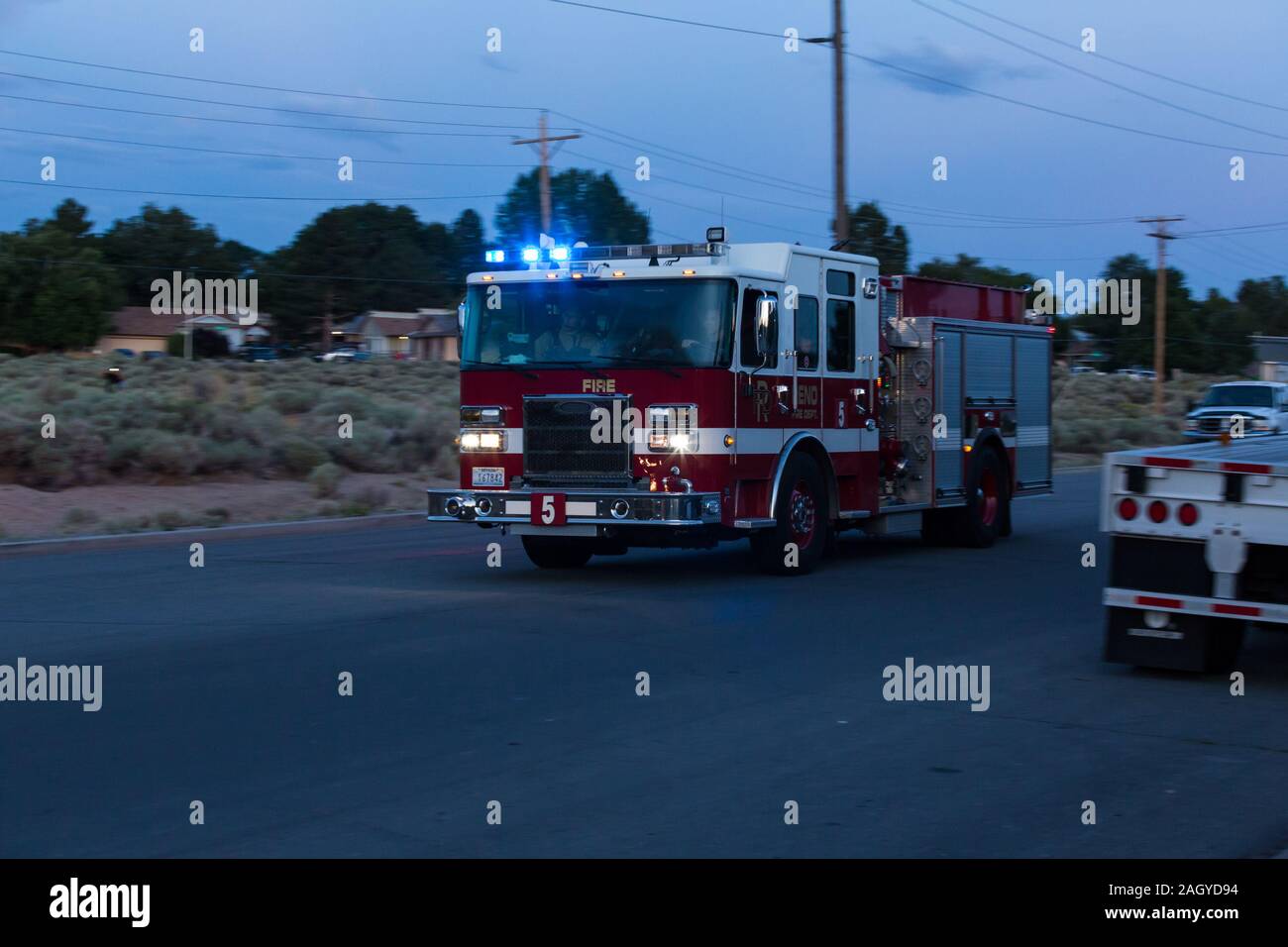 Fire truck responds to call on dark street after sunset with lights and ...