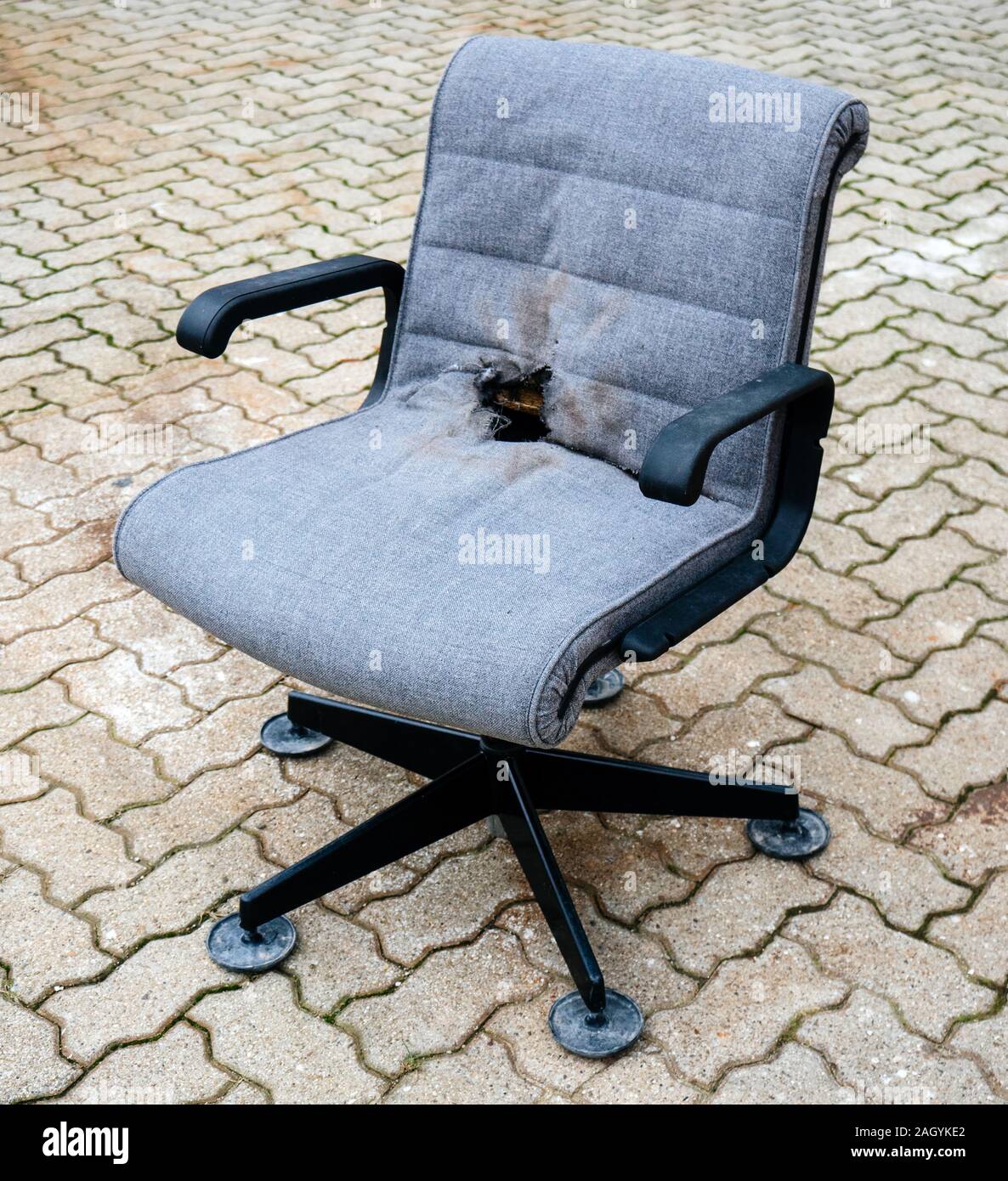Abandoned business large chair with damaged tissue on cobblestone ...