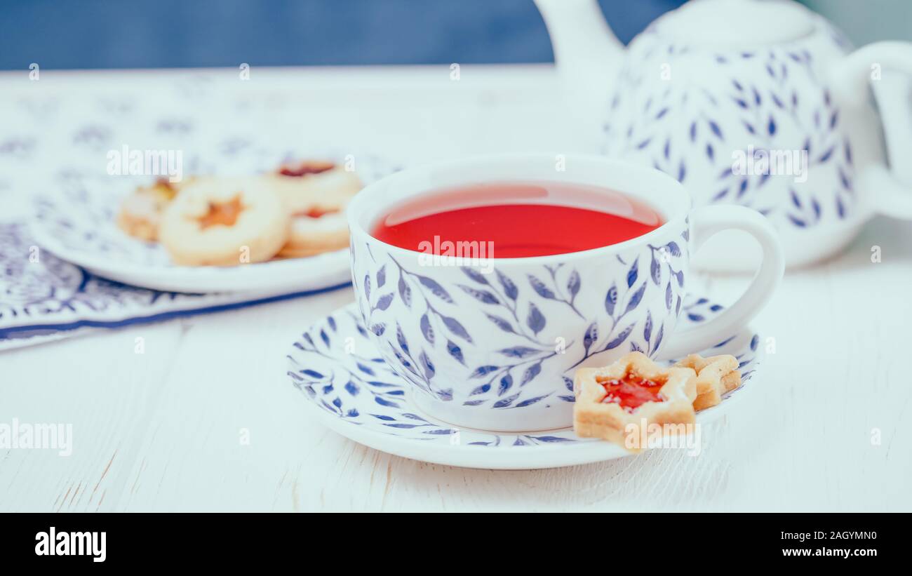 Pink fruit tea and homemade cookies stars with jam on a white wooden ...